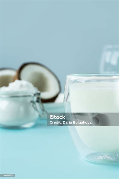 코코넛 제품 고기가 반으로 자른 오픈 코코넛 유리 항아리에 코코넛 파우더 푸른 배경에 우유를 심는 다 등등 투영 공간을 복사합니다 개념 대체 우유 식물성 Charity