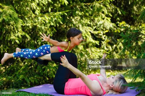 젊은 스포티 한 어머니와 귀여운 어린 딸이 낮에 공원에서 잔디에서 요가 운동을하고 있습니다 친절한 가족과 건강한 라이프 스타일의 개념 2명에 대한 스톡 사진 및 기타 이미지