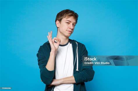 스튜디오에서 파란색 배경에 고립 된 확인 제스처를 보여주는 캐주얼 복장에 자신감 젊은 남자의 초상화 사람들은 진심으로 감정 라이프 스타일 개념입니다 복사 공간을 모의 합니다