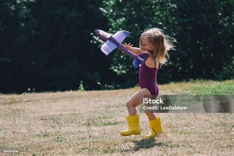 수영복을 입은 어린 소녀가 즐겁게 웃으며 여름에 비행기를 하늘로 발사합니다 한 아이가 비행기로 공터를 통과합니다 행복한 어린 시절 진실한 감정 아이들을위한 활동적인 게임 2