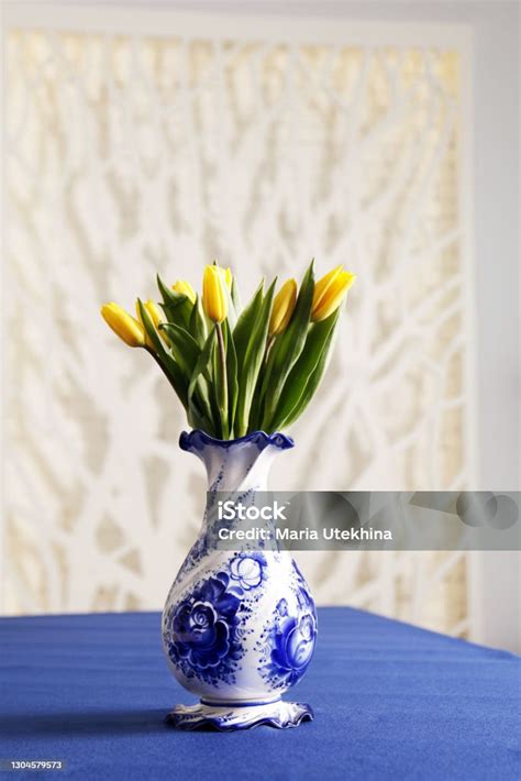푸른색과 흰색 Gzhel 꽃병에 튤립의 신선한 봄 노란색 꽃다발 거실 배경의 밝은 클래식 디자인테이블에 서 선물로 휴일 꽃 인사말 카드의 레이아웃입니다 0명에 대한 스톡