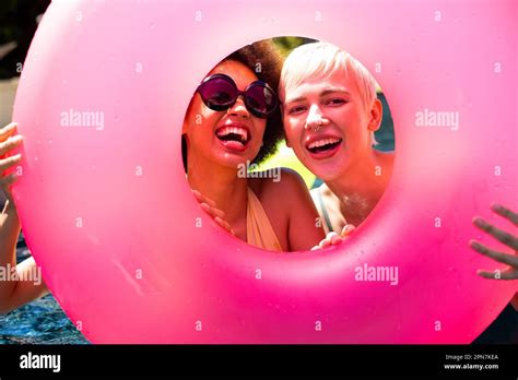 Portrait Of Happy Diverse Female Friends Having Pool Party Holding Swim Ring And Smiling In