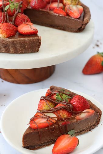 코코아 페이스트리 크러스트 토르트 외에 접시에 초콜릿 딸기 타르트 슬라이스의 클로즈업 이미지 와 전체 와 반으로 딸기 케이크 스탠드에 녹은 초콜릿 대리석 효과 배경 0명에