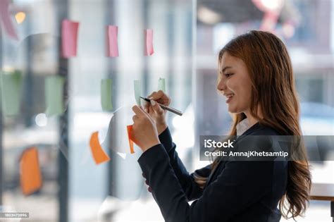 사무실에서 거울에 포스트잇을 붙이는 여성 사업가 브레인스토밍을 하고 사무실의 유리판에 글을 쓰고 있는 여성 사업가 20 24세에 대한 스톡 사진 및 기타 이미지 Istock