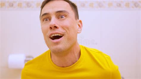 Man Feeling Relieved While Sitting On Toilet In Bathroom Stock Image