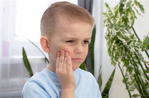 불행한 소년은 집에서 치통으로 고통 받고 있습니다 치아에 치통이나 치과 질환으로 고통스러운 표정으로 손으로 입을 만지는 아이 치과의사 치아 민감도의 개념 4 5세에 대한