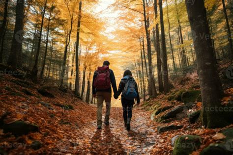 Couple Hiking On A Forest Trail Covered In Colorful Leaves