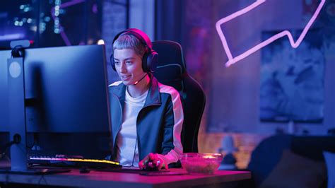 컴퓨터에서 온라인 비디오 게임을 하는 Famouse 여성 게이머 Pvp 토너먼트에서 다른 플레이어와 싸우는 헤드폰을 끼고 있는 행복하고 편안한 여성의 초상화 마이크에서 팀과