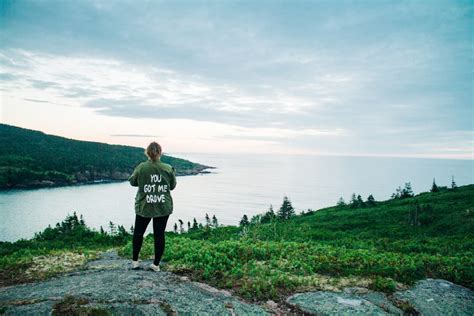 낮 동안 푸른 잔디밭 근처의 회색 콘크리트 통로에 서 있는 녹색 재킷을 입은 여자 사진 Unsplash의 무료 식물 이미지