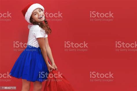 빨간 배경에 고립 된 선물 가방을 들고 산타 모자를 입고 사랑스러운 작은 미소 소녀 텍스트의 공백입니다 12월에 대한 스톡 사진 및 기타 이미지 Istock