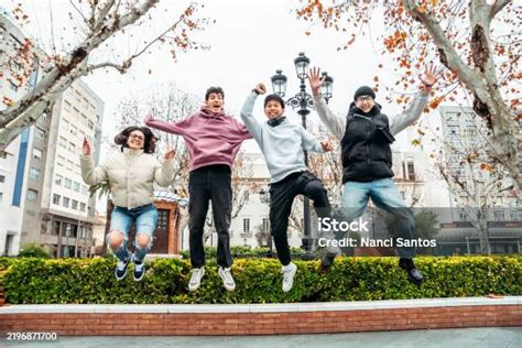 형형색색의 단풍 속에서 함께 뛰어다니는 활기찬 다민족 학생들은 건축을 배경으로 한 도시 공원에서 동지애와 기쁨을 표현합니다 18 19세에 대한 스톡 사진 및 기타 이미지