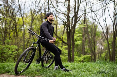 신선한 녹색 여름 숲을 배경으로 서있는 에어 서스펜션 포크가있는 현대적인 카본 하드 테일 자전거의 반바지와 저지를 타는 자전거