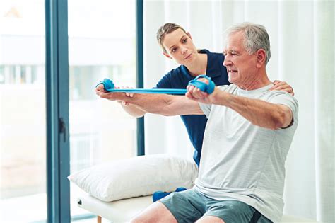 물리 치료 팔 스트레칭과 근육 재활을위한 의료 클리닉 사무실에서 물리 치료사 컨설팅을 가진 노인 의사를 돕는 노인 환자를 위한 관절염 의료 서비스 물리치료에 대한 스톡 사진