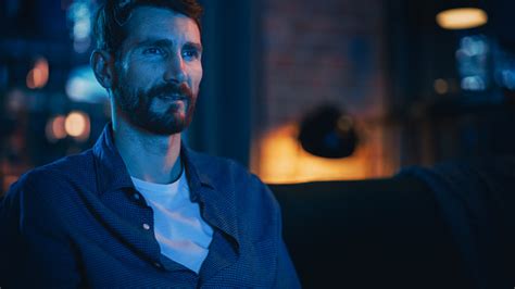 집에서 시간을 보내고 있는 잘생긴 남자의 초상화 소파에 누워 세련된 로프트 아파트의 리모컨으로 Tv로 채널을 전환합니다 영화 스트리밍 서비스 및 휴식에 젊은 남성 켜기