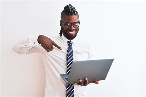 자신에게 손가락을 가리키는 깜짝 얼굴과 고립 된 흰색 배경을 통해 노트북을 사용하여 머리띠와 아프리카 계 미국인 사업가 땋은