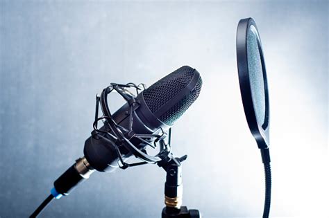 앞에 팝 필터가있는 전문 마이크를 클로즈업하십시오 어두운 배경에 대한 스탠드에서 팟 캐스트 노래 및 스트리밍을 녹음하기위한 데스크톱 마이크 Performing Arts