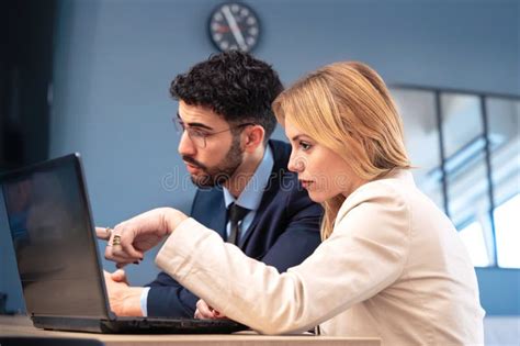 Business Partners Collaborating On Laptop In Modern Office Smiling And Working Stock Image