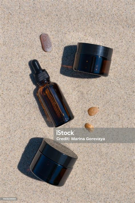젤이 들어간 짙은 호박색 유리 병 히알루 론산이 함유 된 혈청 및 모래 위에 얼굴 크림 천연 Spa 유기농 화장품 뷰티 살롱 브랜딩의 레이아웃 상단 보기 개념에 대한 스톡