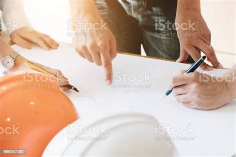 건축가 팀 브레인 스토밍 계획 디자인 사무실 건축 개념에서에서 작은 집 모델 및 안전 헬멧 건설 프로젝트의 청사진을 스케치 하는