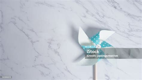 연한 파란색 색상의 일본 특수 소재와 베이 또는 아이들이 놀기 위한 나무 막대기로 만든 종이 접기 손으로 만든 흰색 대리석 돌 배경에 바람 바퀴 종이 실제 장난감 0명에