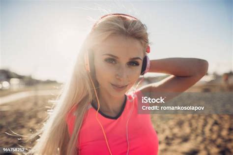 해변에서 음악을 듣고 젊은 아름 다운 여자의 초상화 이어폰 카메라 보고 웃는 금발 여자의 얼굴을 닫습니다 여자 비치에서 실행 하 고 음악을 듣고 Mp3 플레이어에 대한 스톡