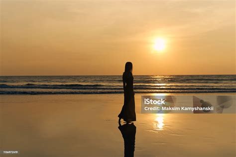 햇볕이 잘 드는 석양 바다와 모래 해변의 배경에 대 한 젊은 날씬한 여자의 대조 실루엣 따뜻한 저녁 색조와 젖은 모래에 그림의 반사 고아 인도에 대한 스톡 사진 및 기타