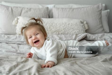 변덕스럽게 울고 있는 아기 소녀는 침대에 누워 카메라를 바라보며 아늑한 침실에서 자고 싶어합니다 땋은 머리를 가진 귀여운 아이 어린 시절 아기기 사람들의 개념 광고에서 공간