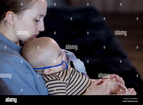 Woman With Infant Son Makes Inhalations Using A Nebulizer At Home Stock