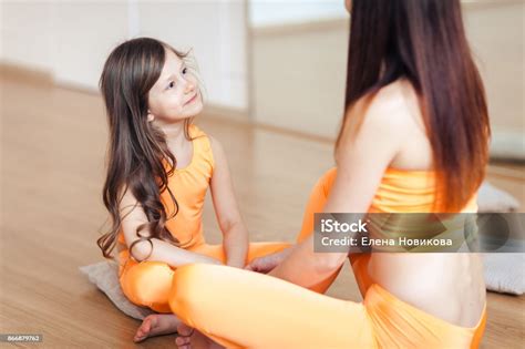 밝은 오렌지 스포츠 슈트에 갈색 머리 소녀는 바닥에 앉아서 엄마에 보인다 어머니와 대화 2명에 대한 스톡 사진 및 기타 이미지 2명 가족 개념 Istock