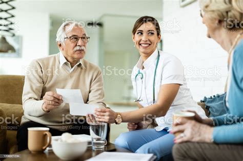 행복한 헬스케어 노동자와 노인 부부는 가정 방문 중에 사진 앨범을보고 가정 생활에 대한 스톡 사진 및 기타 이미지 가정 생활 건강관리와 의술 노인 Istock