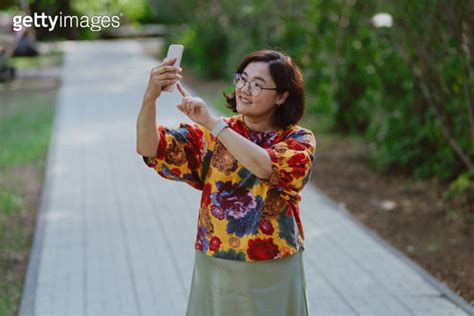 Cheerful Young Lady With Glasses Capturing A Selfie In A Lush Green