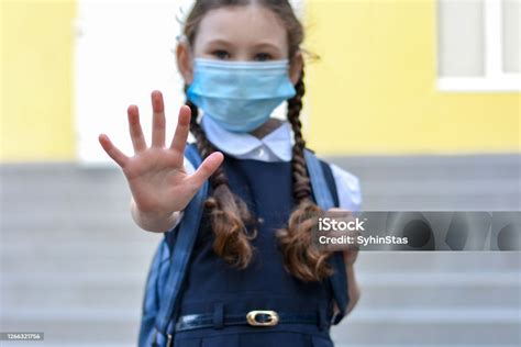 의료 용 마스크의 여학생은 코로나 바이러스와 거리 학습을 중지 제스처를 보여줍니다 아이들은 새로운 정상으로 학교에 간다 코로나바이러스 학교로 돌아가기 붐비는 장소에서 안전의