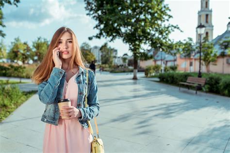 아름다운 유행과 세련된 소녀 도시에서 여름에 그녀의 휴대 전화에 전화 인터넷에서 메시지를 듣고 도시 공원에서 휴식을 가지고있다 텍스트 공간 커피 차 한 잔 감탄에 대한 스톡