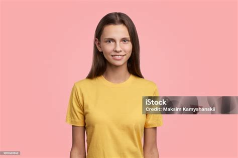 예쁜 십 대 소녀의 사진 카메라 긴 머리에 심각한 모습 부드러운 미소 그녀의 자연의 아름다움을 보여줍니다 광고에 대 한 복사 공간 핑크 배경 십 대 포즈 갈색 머리에 대한