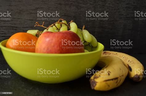 4 종류의 과일 사과 키노우 녹색 그릇에 담긴 포도와 옆에 바나나 두 개가 있습니다 검은 배경입니다 맛있고 영양가 있고 육즙이 많은 달콤한 과일 음식 인도 0명에 대한 스톡