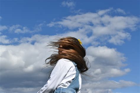 흰 구름과 푸른 하늘 아래 머리에 노란 꽃이 달린 흰 셔츠를 입은 여자 사진 Unsplash의 무료 여자 이미지