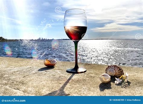 Glass Of Red Wine On Beach Stone And Seashells Nature Panorama Blue Sky