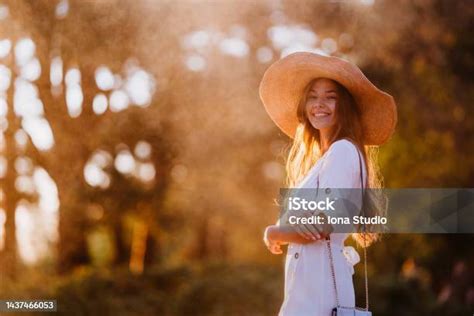 밀짚 모자를 쓴 젊은 호주 여성 여행자 여성 버튼이 달린 흰색 드레스 야생 숲에 서 있는 모자를 만지는 카메라를 보고 있습니다 매력적인 소녀 여행 레저 자연의 사람들 25