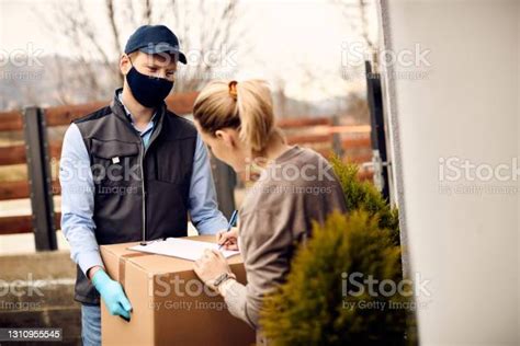 고객이 택배를 수령한 문서에 서명하는 동안 골판지 상자를 들고 얼굴 마스크를 가진 배달 남자 배달에 대한 스톡 사진 및 기타 이미지 Istock