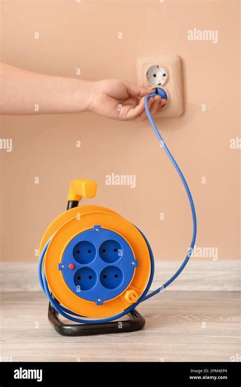 Woman Plugging Extension Electric Cable Into Socket Near Color Wall Stock Photo Alamy
