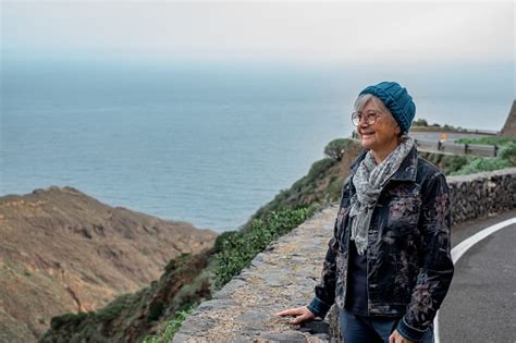 카나리아 제도의 라 고메라에서 야외 여행을 떠나는 노인 여행자 여성은 언덕 꼭대기에서 풍경과 바다 전망을 바라보고 있다 물 위의 수평선 감탄에 대한 스톡 사진 및 기타