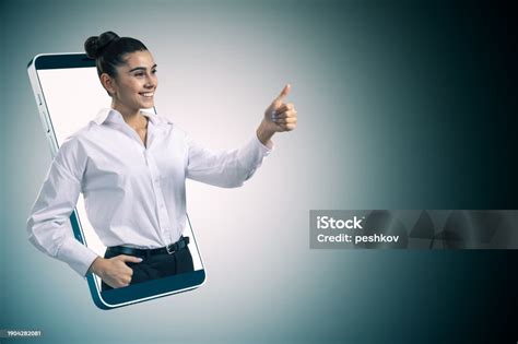 행복 한 젊은 유럽 여자 안에 스마트 폰 모형 장소와 회색 배경에 엄지 손가락을 보여줍니다 인터넷 통신 온라인 비디오 메시징 및 원격 작업 개념 Brand Name