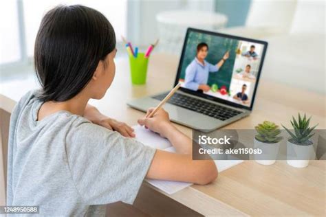 아시아 소녀 비디오 컨퍼런스 E러닝 교사와 급우와 함께 집에서 거실에서 컴퓨터에서 컴퓨터 홈 스쿨링 및 거리 학습 온라인 교육 및 인터넷 전자 학습에 대한 스톡 사진 및
