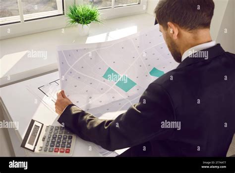 Male Professional Engineer Analyzing Cadastral Map In Office Stock