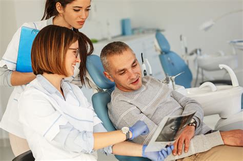 치과 의사와 치과 진료소에서 그녀의 조수는 남성 환자와 이야기하고 치료를 준비합니다 X 레이에 대한 스톡 사진 및 기타 이미지 X 레이 건강 진단 건강관리와 의술