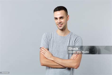 웃 고 잘생긴 젊은 남자 캐주얼의 옷 카메라를 찾고의 초상화 손을 잡고 스튜디오에서 회색 배경에 고립 된 교차 사람들은 진심으로 감정 라이프 스타일 개념입니다 복사 공간을