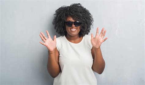 젊은 아프리카계 미국인 플러스 크기 여자에 회색 화 축 하 패션 선글라스를 착용 하는 그런 지 벽 무기와 성공을 위해 미친 제기