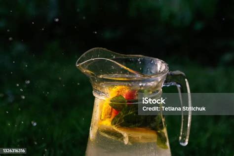 물 방울과 자연 녹색 배경에 슬라이스 레몬과 민트레모네이드의 디포커스 유리 주전자 신선한 추운 여름 햇볕이 잘 드는 칵테일 또는 야외 펀치의 투수 공간을 복사합니다 튀김