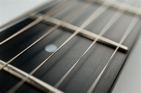 기타 지판의 클로즈업 샷으로 장인 정신 복잡한 프렛 나뭇결 질감을 강조합니다이 이미지는 깊이를 전달하고 관람객이 기타 연주를 상상하도록 초대합니다 각도에 대한 스톡 사진 및