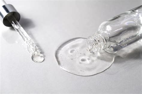 회색 배경에 유리 병과 파이펫에서 쏟아지는 투명한 얼굴 세럼 히알루론산 클로즈업화장품 뷰티 루틴 히알루론산에 대한 스톡 사진 및